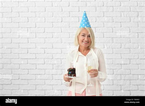 Mature Woman With Piece Of Birthday Cake And Glass Of Champagne On
