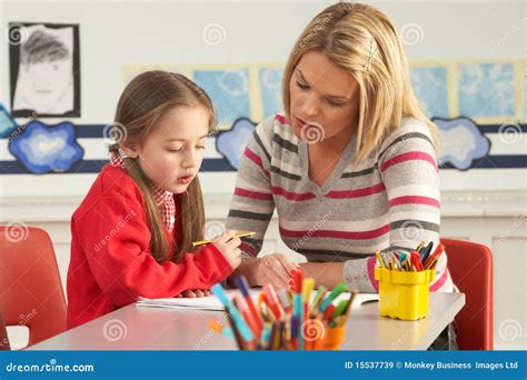 Female Primary School Teacher Sitting On The Floor In A Classroom