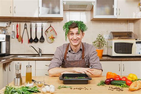 미친 재미 젊은이 앞치마 머리에 딜와 회 향 테이블에 앉아에 집에서 요리 쇠고기 돼지고기에서 고기 스테이크를 준비 또는 어린 양 나무 표면 멋진 주방의 전체 빛 부엌에