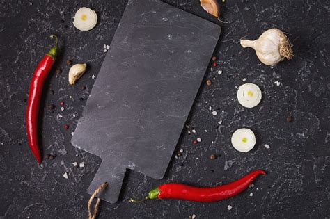 Cutting Board And Red Hot Chili Pepeprs On Black Stone Background Top