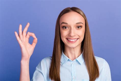 若い満足した陽気な笑顔の幸せなスタイリッシュな茶色の女性はパステル背景に孤立したオッケーオッケージェスチャーを示します Premium写真