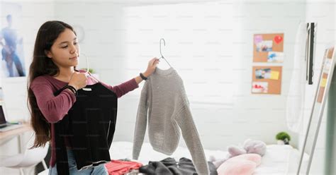 침실에 있는 귀여운 십대 소녀가 밤에 무엇을 입을지 고민하고 있다 거울 앞에서 다른 의상을 입어보는 예쁜 십대 사진 Unsplash의 성인 이미지