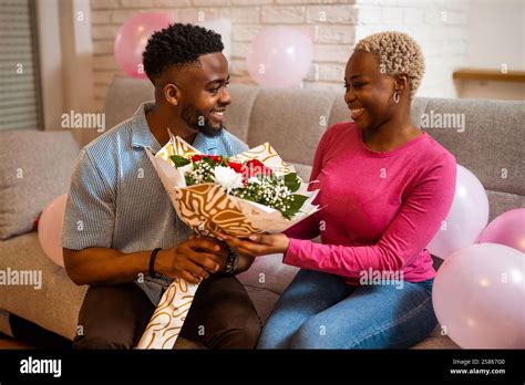 Happy Loving Couple Celebrating Woman S Birthday At Home Boyfriend Is Giving Bouquet Of Flowers