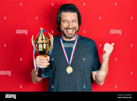 Middle Age Caucasian Man Holding Champion Trophy Wearing Medals