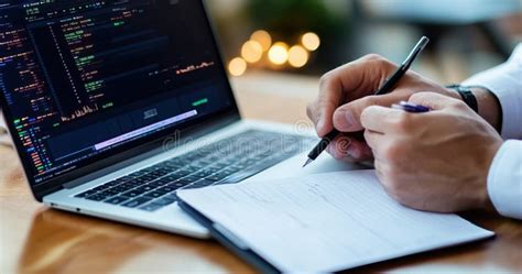 A Forex Trading Expert Writing Notes On A Paper Pad Next To A Running