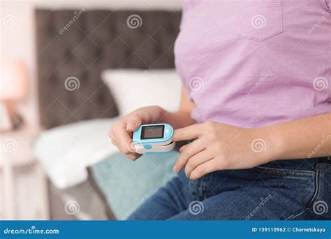 Young Woman Checking Pulse With Digital Medical Device Indoors Closeup