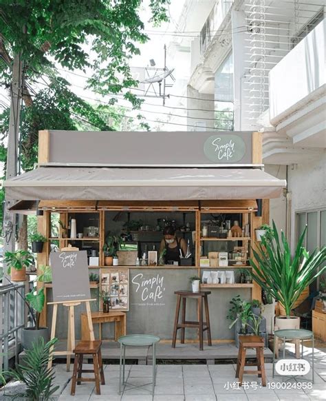 An Outdoor Cafe With Tables And Stools In Front Of The Counter Surrounded By Greenery