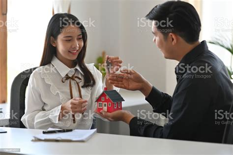 사무실에 앉아 부동산 계약에 대한 합의를하고 주택 금융 및 부동산 사업을위한 열쇠와 레드 하우스 모델을 제공하는 사업가의 초상화