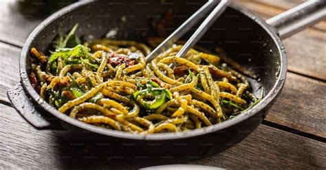 핀셋이 들어있는 어두운 팬에 페스토와 파마산 치즈를 곁들인 스파게티 사진 Unsplash의 미식가 이미지