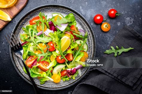 다채로운 토마토 신선한 오이 적양파 양상추 루꼴라를 곁들인 여름 비건 야채 샐러드 검은색 테이블 배경 평면도 건강한 식생활에