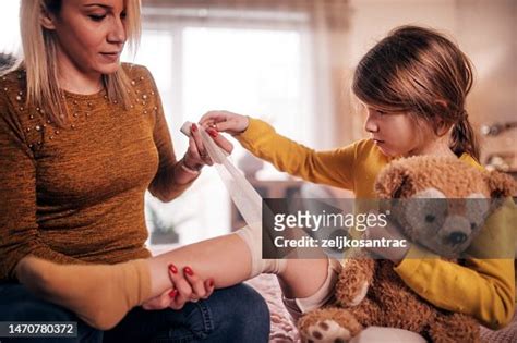 Mom Bandages Her Daughters Leg And Play With A Teddy Bear High Res