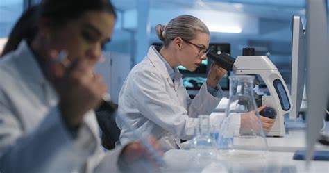 생명 공학 분석 및 연구 협업을 위한 현미경을 사용하는 과학자 테스트 및 실험실 바이러스 또는 건강에 대한 백신 치료를 위한 과학 혁신을 위해 노력하는 미래 실험실 및 여성