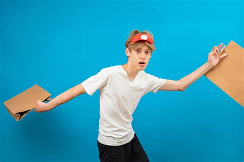 파란색 배경 스튜디오 초상화에 종이 가방이 달린 캐주얼 한 흰색 티셔츠를 입은 젊은 남자 판매자 사람들의 라이프 스타일 개념 복사 공간을 모의합니다 쇼핑 후 구매시 패키지