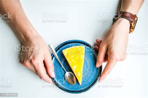 고립 된 흰색 테이블에 수제 파인애플 치즈 케이크의 슬라이스 조각으로 접시를 만지는 여성의 손의 상단보기 치즈케이크에 대한 스톡