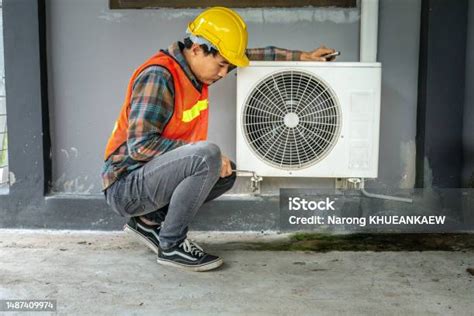 에어컨 기술자는 렌치를 사용하여 공기 압축기의 너트를 조입니다 젊은 아시아 남자 수리공이 외부 에어컨 장치를 점검합니다 35