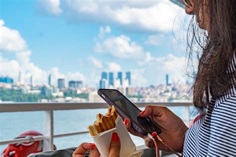 바다 여행 중에 전화를 사용하고 샌드위치를 먹는 젊은 여성 Brand Name Online Messaging Platform에 대한 스톡 사진 및 기타 이미지 Brand