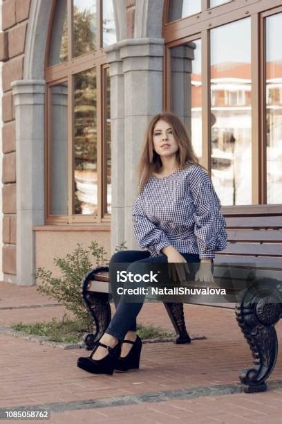 그녀의 다리를 이동 하는 도시 배경에서 벤치에 앉아 아프로 헤어스타일으로 젊은 흑인 여자 혼합된 여자 캐주얼 옷을 입고입니다