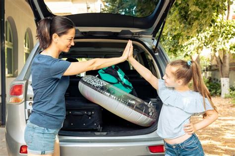 Mulher e menina fazendo highfive antes de sair em viagem de férias à beira mar carregando