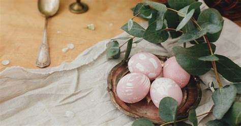 바구니와 촛불이 있는 소박한 나무 테이블에 유칼립투스 가지가 있는 현대 부활절 달걀 세련된 파스텔 핑크 부활절 달걀은 사탕무에서 천연 염료로 칠해졌습니다 행복한 부활절