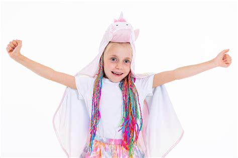 사랑스럽고 예쁜 아이는 카메라를 바라보며 웃고 엄지손가락을 치켜들고 스튜디오에서 하얀 배경에 서서 포즈를 취하는 동안 거리를 바라보며 웃고 있다 귀여운에 대한 스톡 사진 및