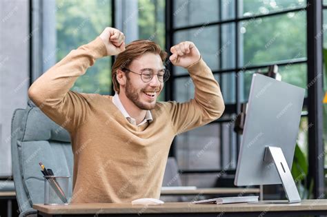 Premium Photo Smiling Young Male Programmer Freelancer Sits At The Table Looks Happy At The
