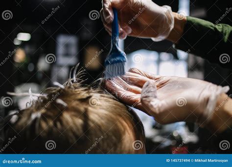 Hairdresser With A Brush To Apply Hair Dye Coloring In The Barber Shop