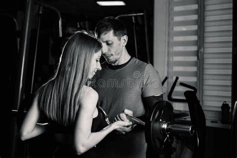 Handsome Athletic Man Training Biceps Barbell In The Gym With The Help