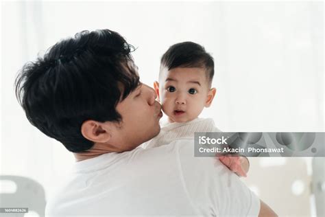 아버지의 행복 사랑스러운 아기를 손에 들고 있는 젊은 아시아 아빠가 집 창가에 서 있다 갓난아기와 함께 시간을 보내는 사랑하는 아버지 아버지의 날 개념입니다 2 5 개월에