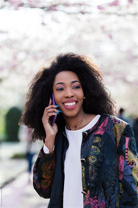 Young Black Woman Smiling While Talking On The Phone Outdoors By