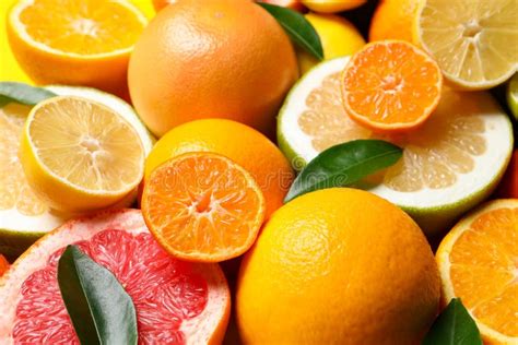 Different Ripe Citrus Fruits With Green Leaves As Background Closeup