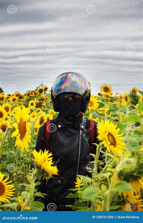 A Girl In A Motorcycle Helmet Stands In A Field With Sunflowers In Non