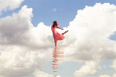 海滩上美丽的女人，迷人的穿着粉红色的裙子跳舞，