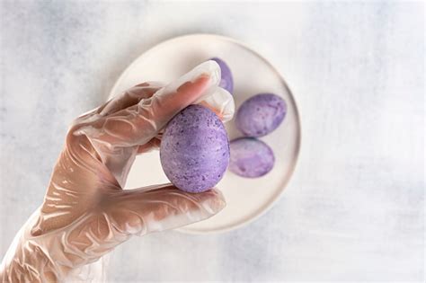 여자의 손은 보라색 부활절 달걀을 들고 있다 히비스커스 꽃에서 천연 염료 차와 부활절 달걀을 색칠 대리석 효과와 트렌디 한 매우