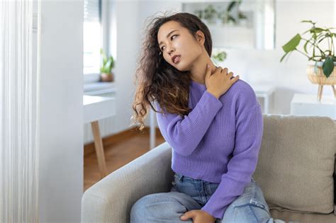 집에서 요통으로 고통받는 아시아 여성 허리 통증 여자는 아픈 근육을 마사지하는 허리 통증을 느끼고 슬픈 여자는 허리로 고통