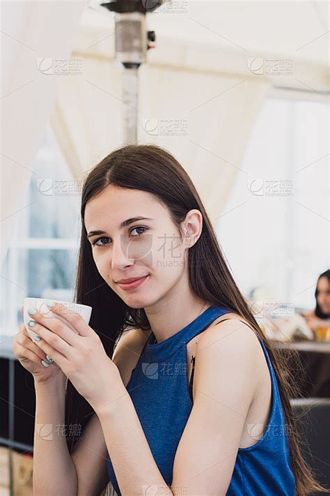 一个非常漂亮的女商人坐在咖啡馆里，手里拿着一杯咖啡