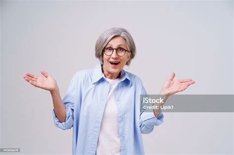 스튜디오에서 흥분한 성숙한 여성 하얀 배경에 고립 된 파란색 셔츠에 흥분을 더듬는 노인 여성 50 59세에 대한 스톡 사진 및