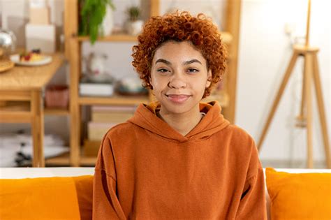 아프리카 헤어스타일을 한 아름다운 아프리카계 미국인 소녀가 집 실내 소파에 앉아 웃고 있다 곱슬머리를 한 젊은 아프리카 여자가 웃고 있다 자유 행복 평온 행복한 사람들의