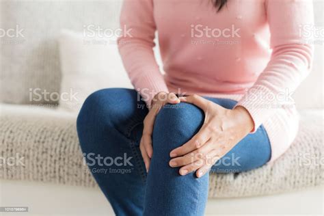 근접 촬영 젊은 여 자가 소파와 느낌 무릎에 앉아 고 통과 그녀 마사지 그녀의 무릎을 집에서 의료 및 의료 개념입니다 건강관리와