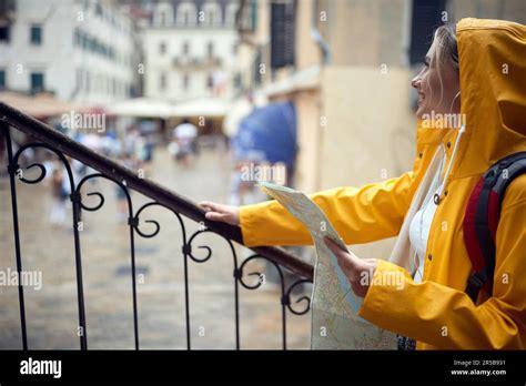 Travel In City In Rain Young Woman In Yellow Raincoat Hiding From Rain