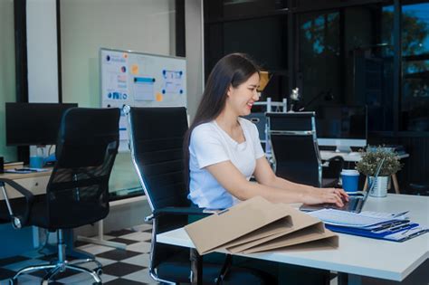 한 젊은 아시아 여성이 낮에는 사무실의 책상에서 일합니다 재무 차트 파일 및 장치에 둘러싸여 그녀는 신용 보고서 계산 및 신용 위험 평가에 대한 컨설팅을 제공합니다 25