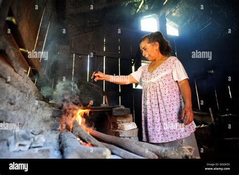 Elderly Woman In A Basic Kitchen Cooking On An Open Fire Carayao