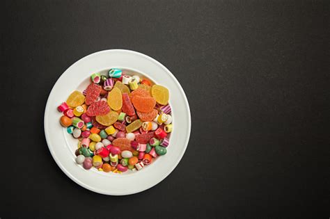 검은 배경에 흰색 접시에 맛 있는 여러 가지 빛깔의 카라멜 사탕과 감귤 젤리의 평면도 복사 공간 0명에 대한 스톡 사진 및 기타