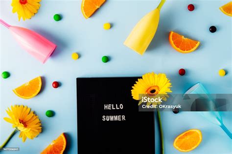 안녕하세요 여름 비문 노란색 거베라 꽃 주황색 조각 밝은 칵테일 잔 밝은 파란색 배경에 여러 가지 빛깔의 사탕 방울이 있는 편지판의 평면도 평면 여름 파티 분위기 감정에