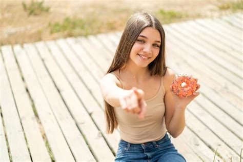 Premium Photo Teenager Girl Holding A Donut At Outdoors Points Finger