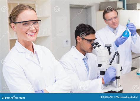 Smiling Scientist Looking At Camera While Colleagues Working With Microscope Stock Image Image
