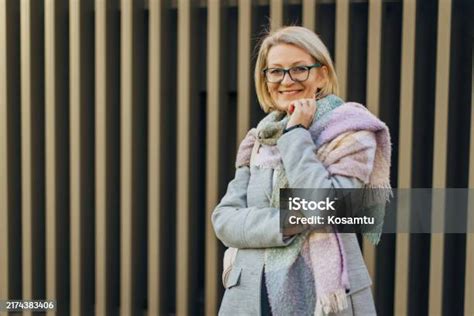 겨울 코트와 스카프를 착용한 채 건물 외관 앞에 서 있는 행복하고 자신감 넘치는 노인 여성의 허리 위로 보이는 모습 여자에 대한 스톡 사진 및 기타 이미지 Istock