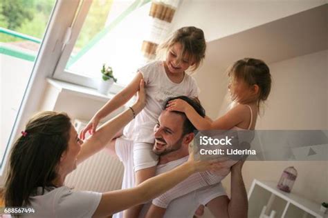 침대에 함께 재생 하는 명랑 한 가족 부모 그들의 딸과 함께 자유 시간을 보내고입니다 딸은 아버지의 어깨에 앉아입니다 4 명에