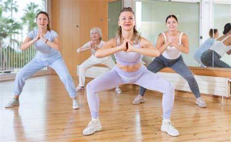 Group Of Positive Sporty Women Of Different Ages In Activewear Performing Squats Before Dance