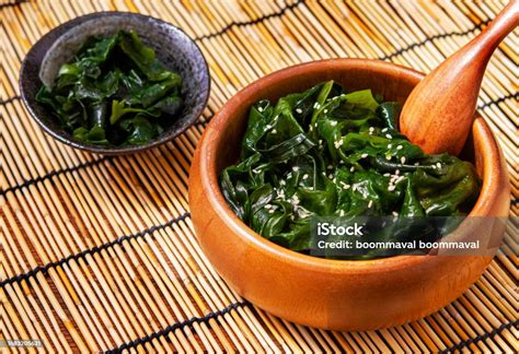 Laminaria 테이블 배경에 나무 그릇에 참깨가 있는 해초 미엽 무침 한국 김 샐러드 Dashi Broth에 대한 스톡 사진
