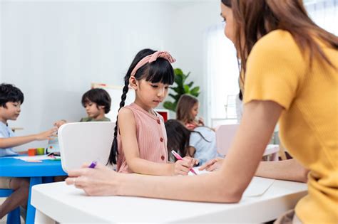 아시아의 아름다운 젊은 여성 선생님이 학교에서 아이에게 공과를 가르칩니다 매력적인 여성 강사 마스터가 유치원 교실에서 재미있는